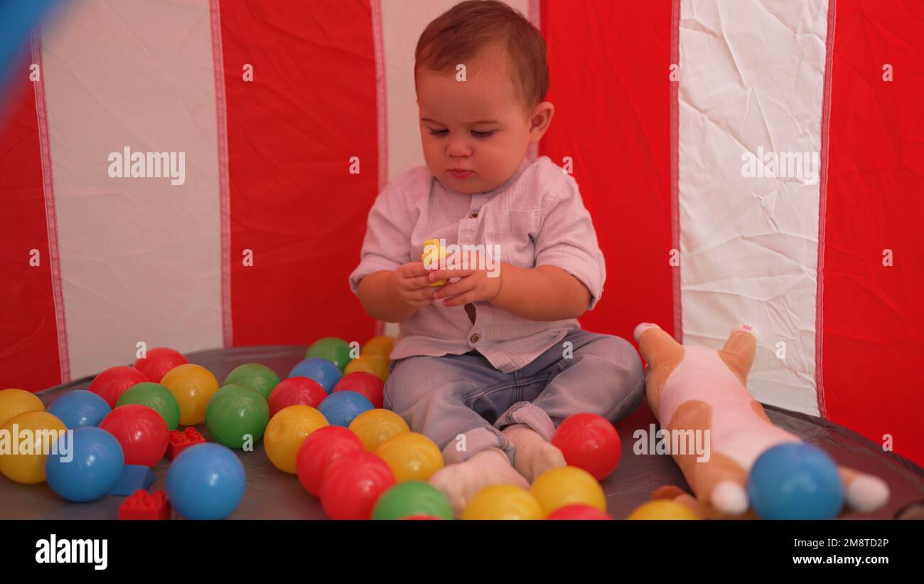 Adorable toddler playing with toys sitting inside of circus tent at ...
