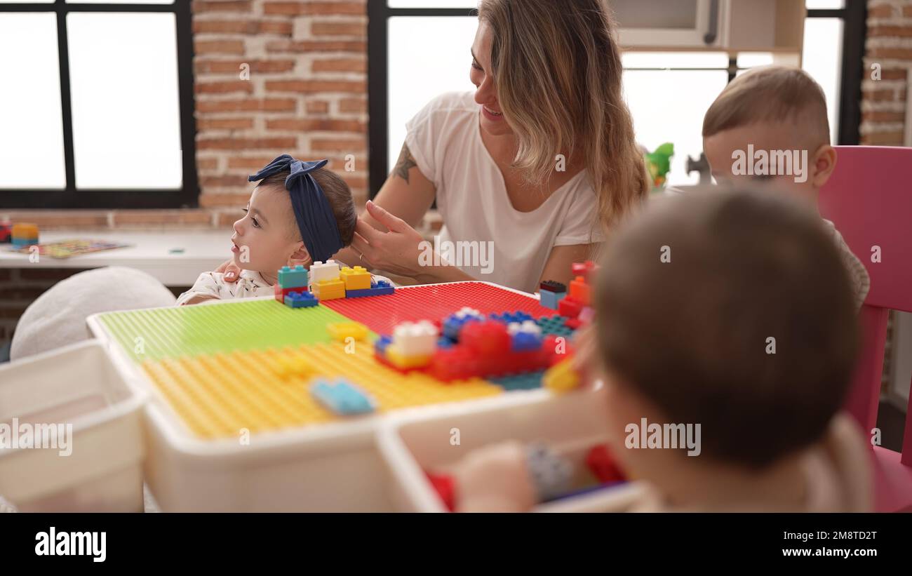 Teacher and preschool students playing with construction blocks sitting ...