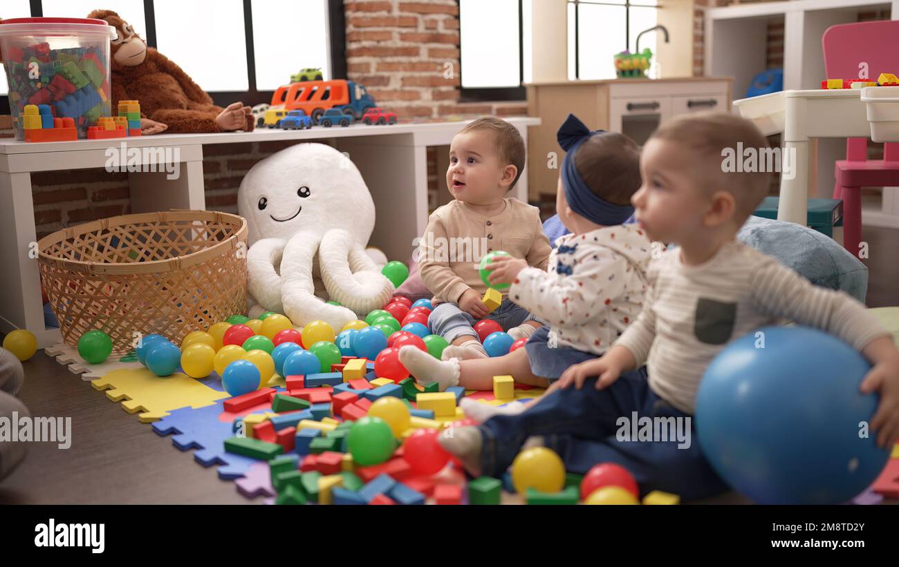 Group of toddlers playing with toys sitting on floor at kindergarten ...