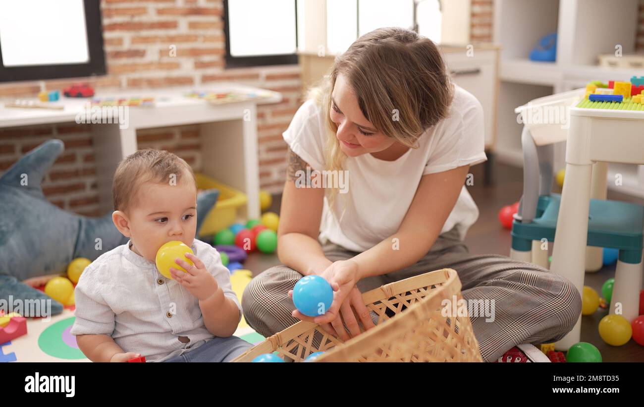 Mother and son sucking ball sitting on floor at kindergarten Stock ...
