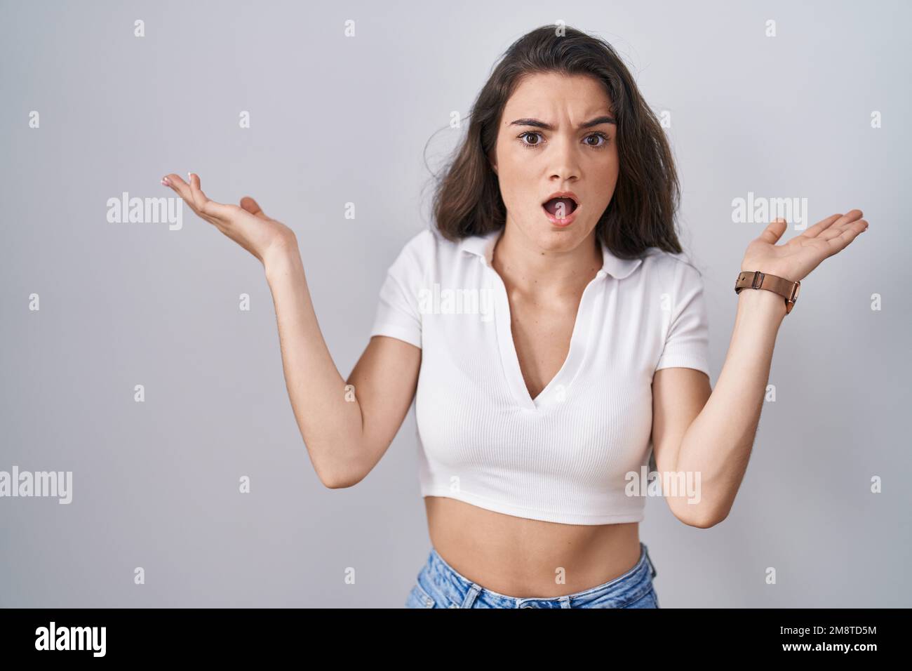Young teenager girl standing over white background clueless and ...