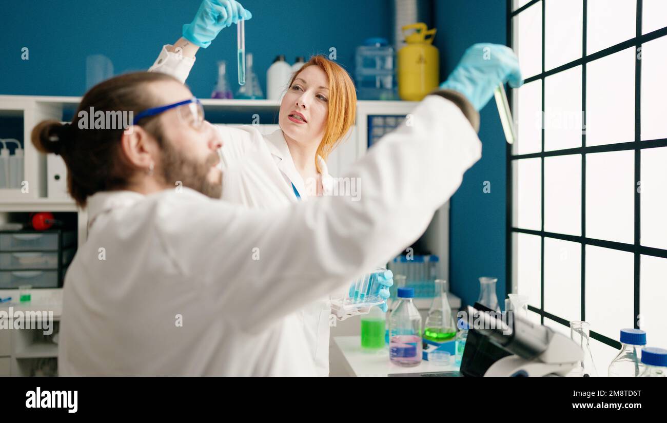 Man and woman wearing sciencist uniform holding test tubes at ...