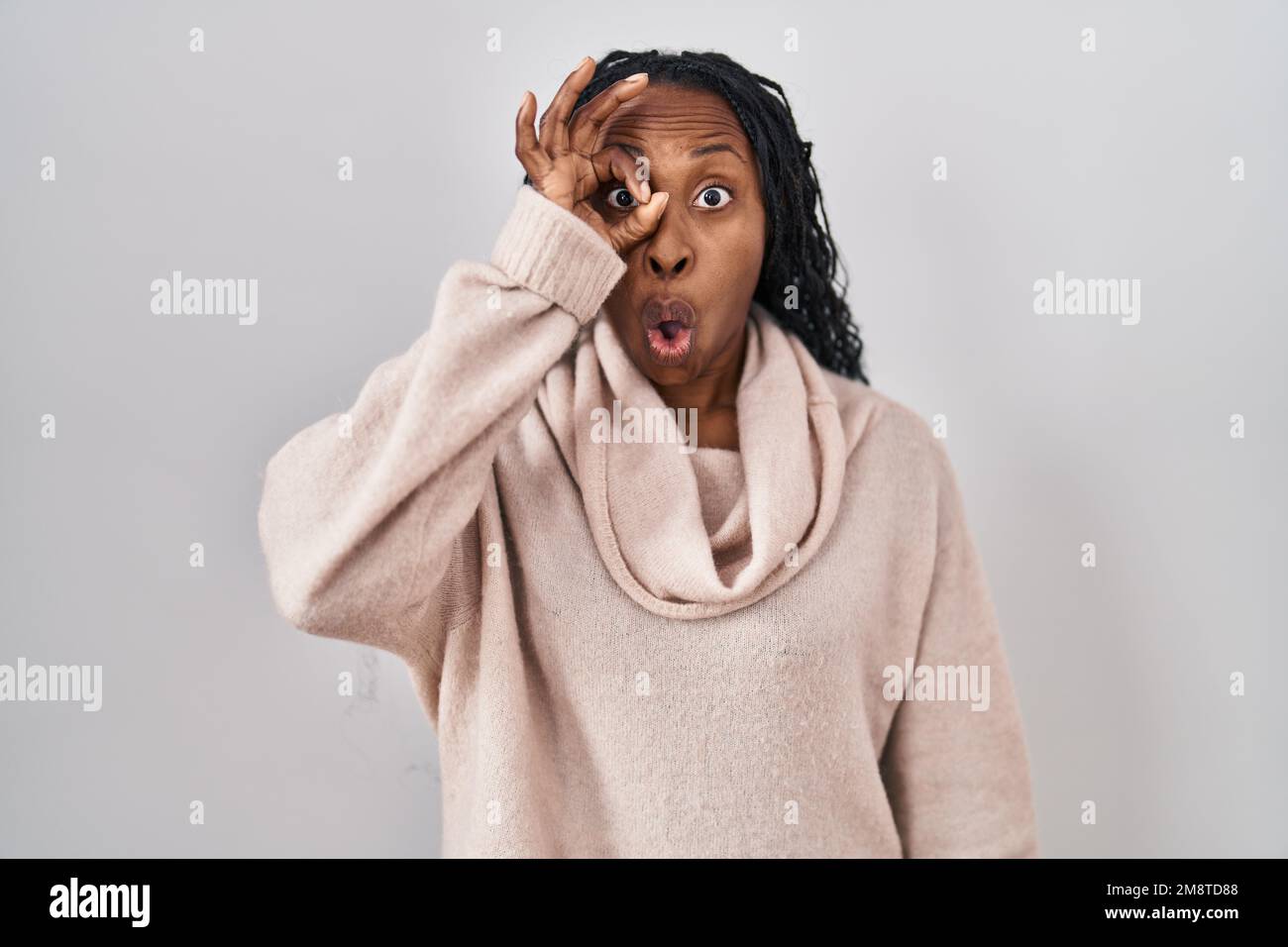 African woman standing over white background doing ok gesture shocked ...