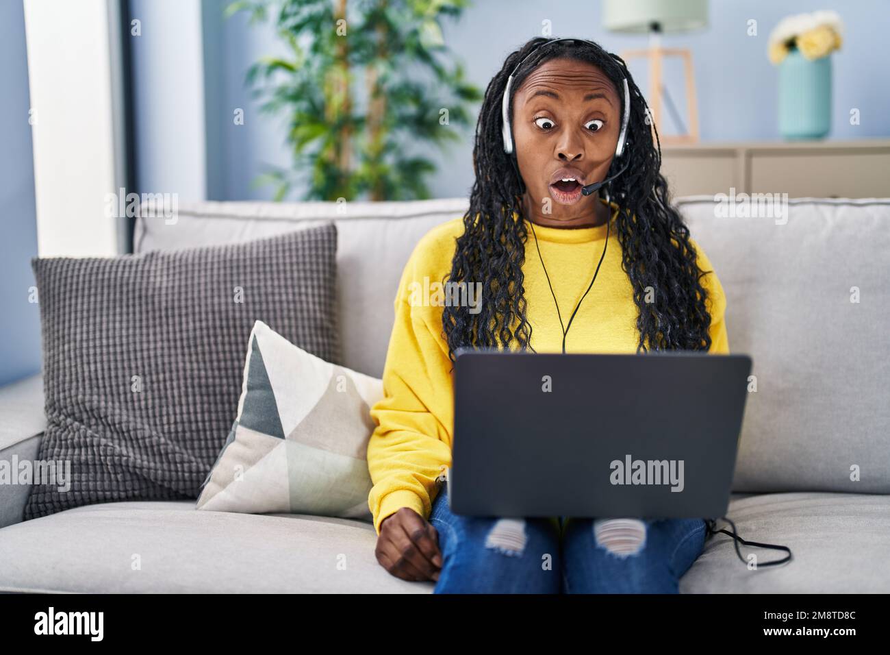 African woman working at home wearing operator headset scared and ...