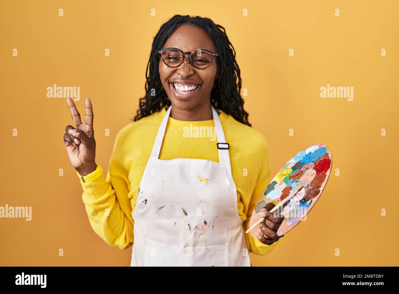 African woman holding painter palette smiling with happy face winking ...