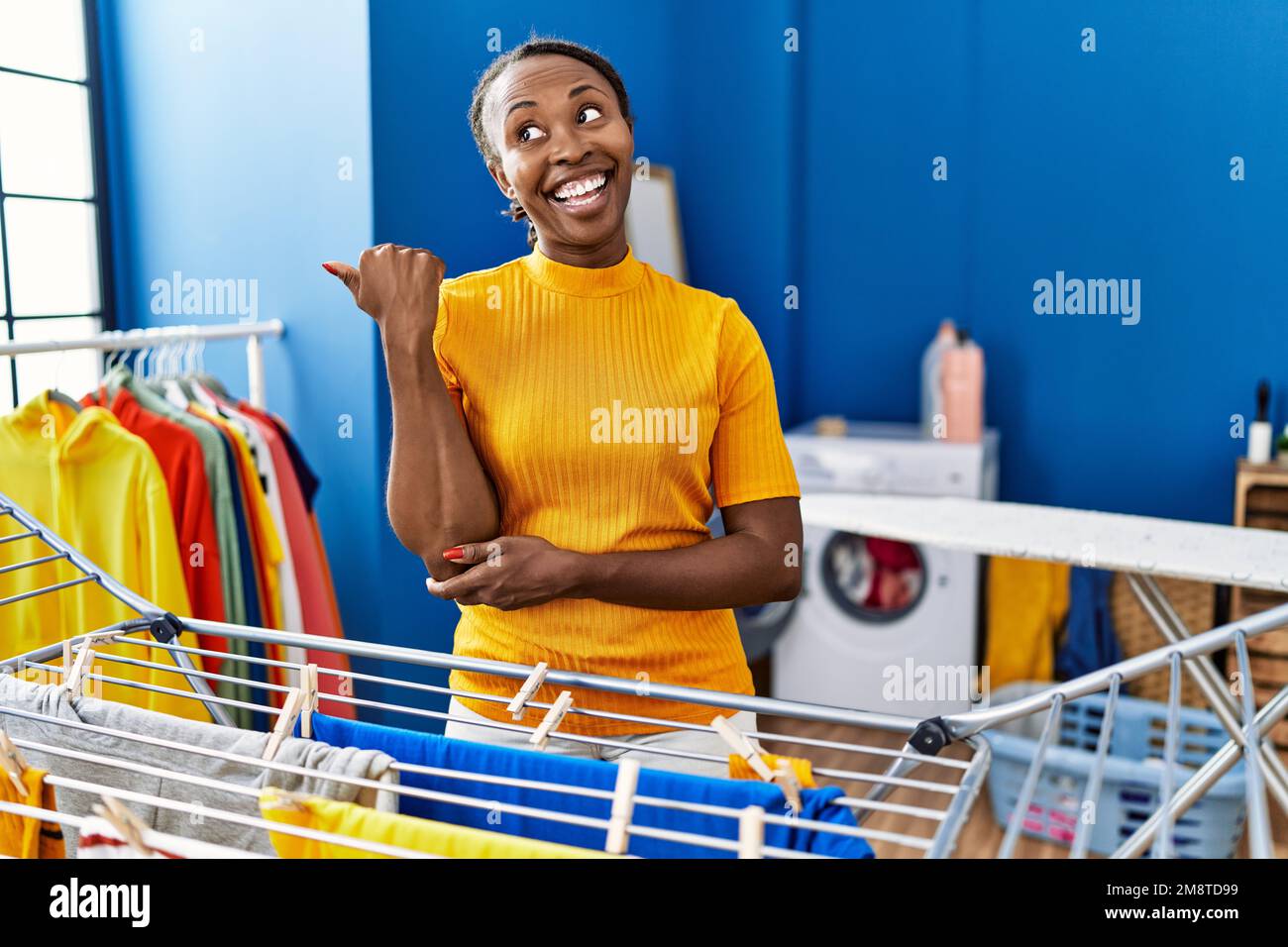 African woman hanging clothes at clothesline smiling with happy face ...