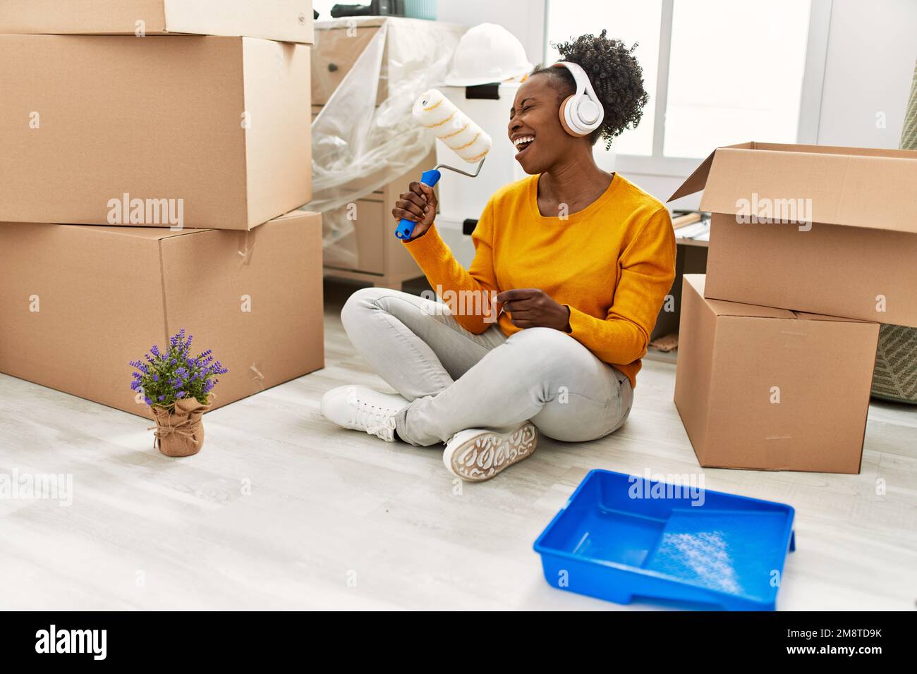 African american woman listening to music singing song at new home ...