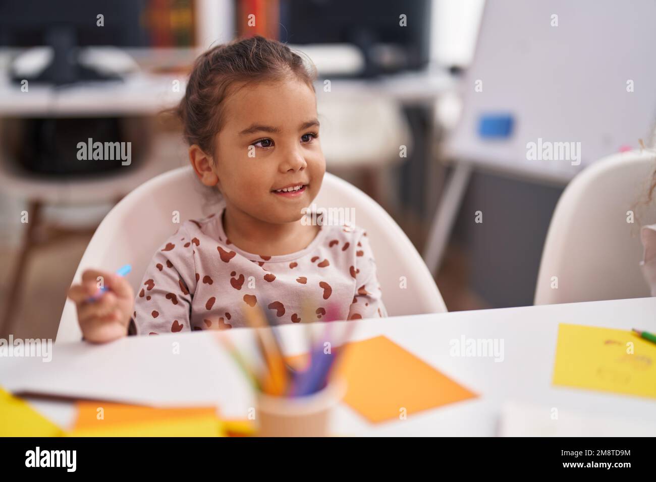 Adorable hispanic girl student sitting on table drawing on paper at ...