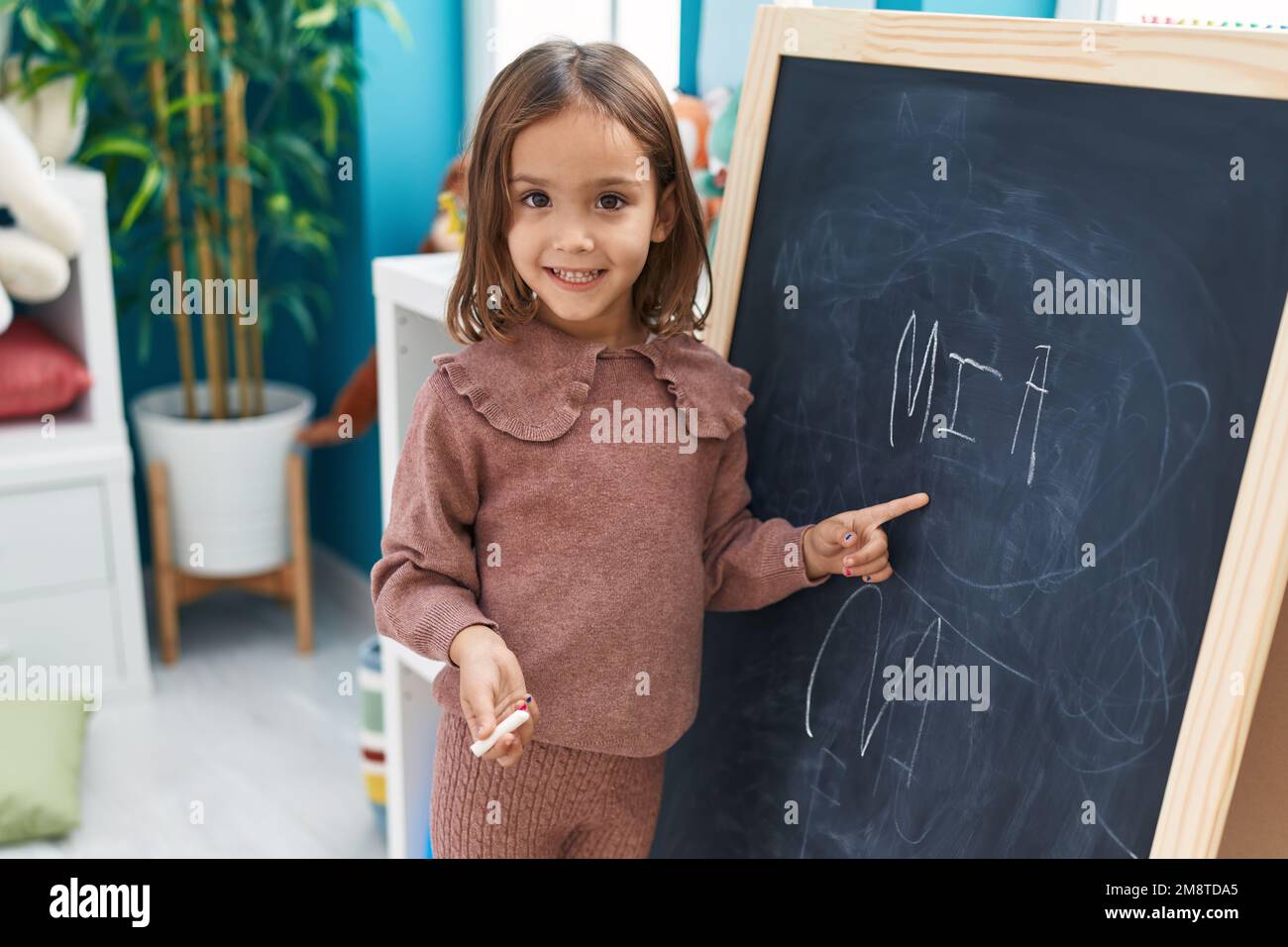 Adorable hispanic girl preschool student smiling confident writing name ...