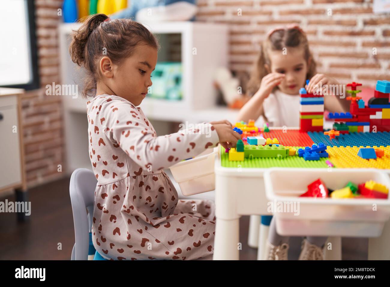 Two kids playing with construction blocks sitting on table at ...