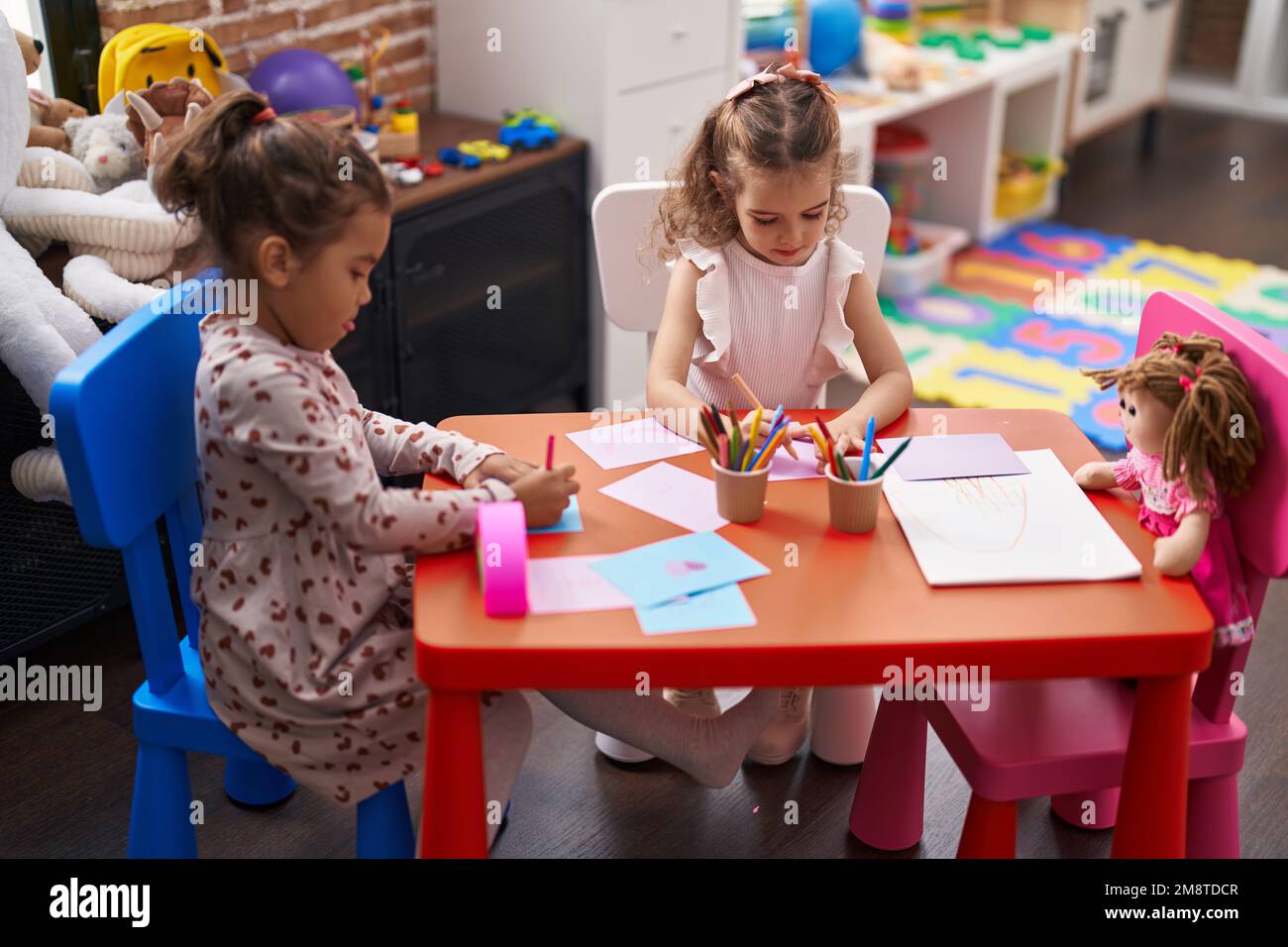 Two kids preschool students sitting on table drawing on paper at ...