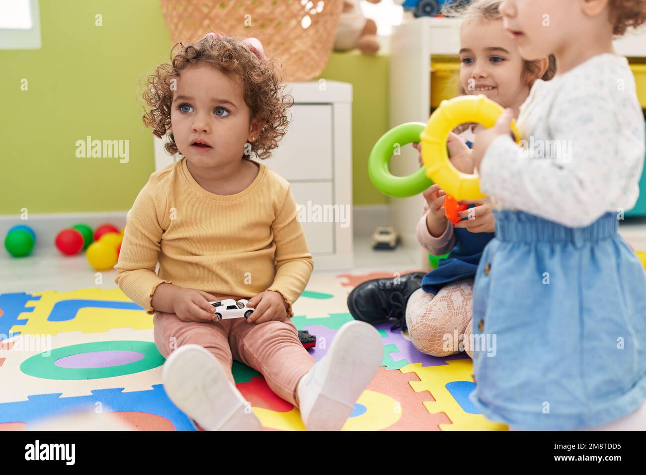 Group of kids playing with hoops toys sitting on floor at kindergarten ...