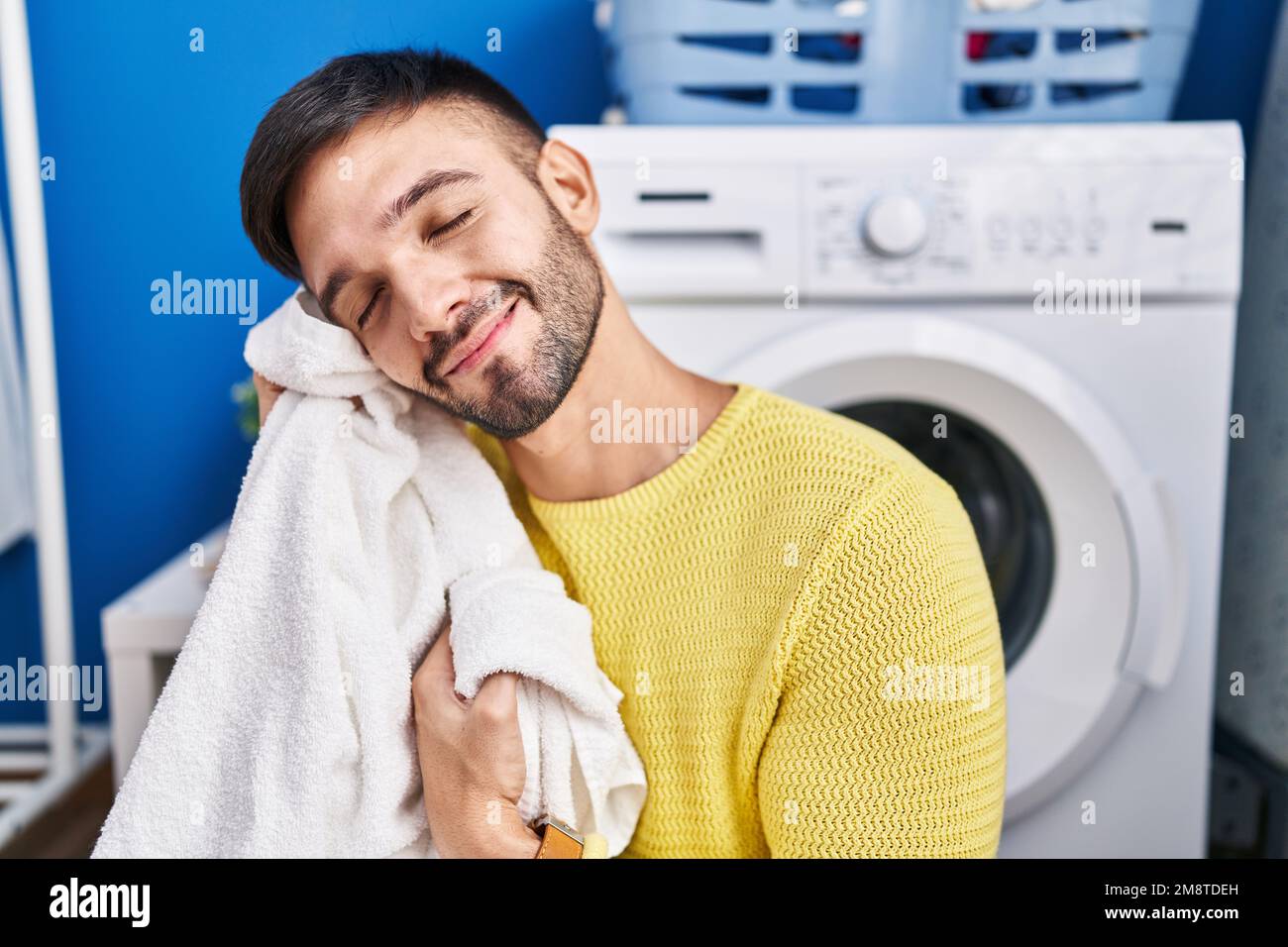 Young hispanic man smiling confident touching softener clothes with ...