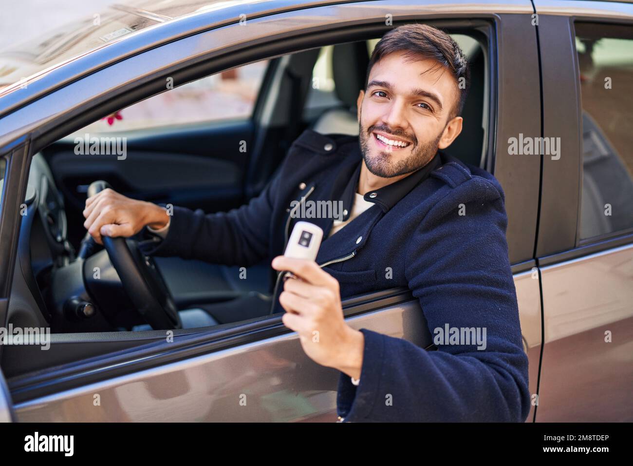 Young hispanic man smiling confident holding key of new car at street ...