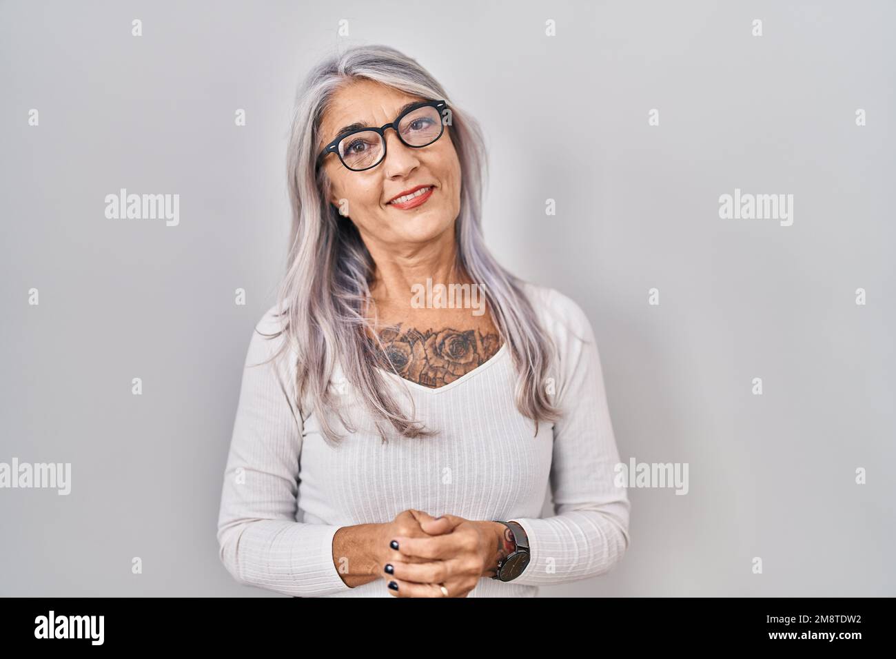 Middle age woman with grey hair standing over white background with ...