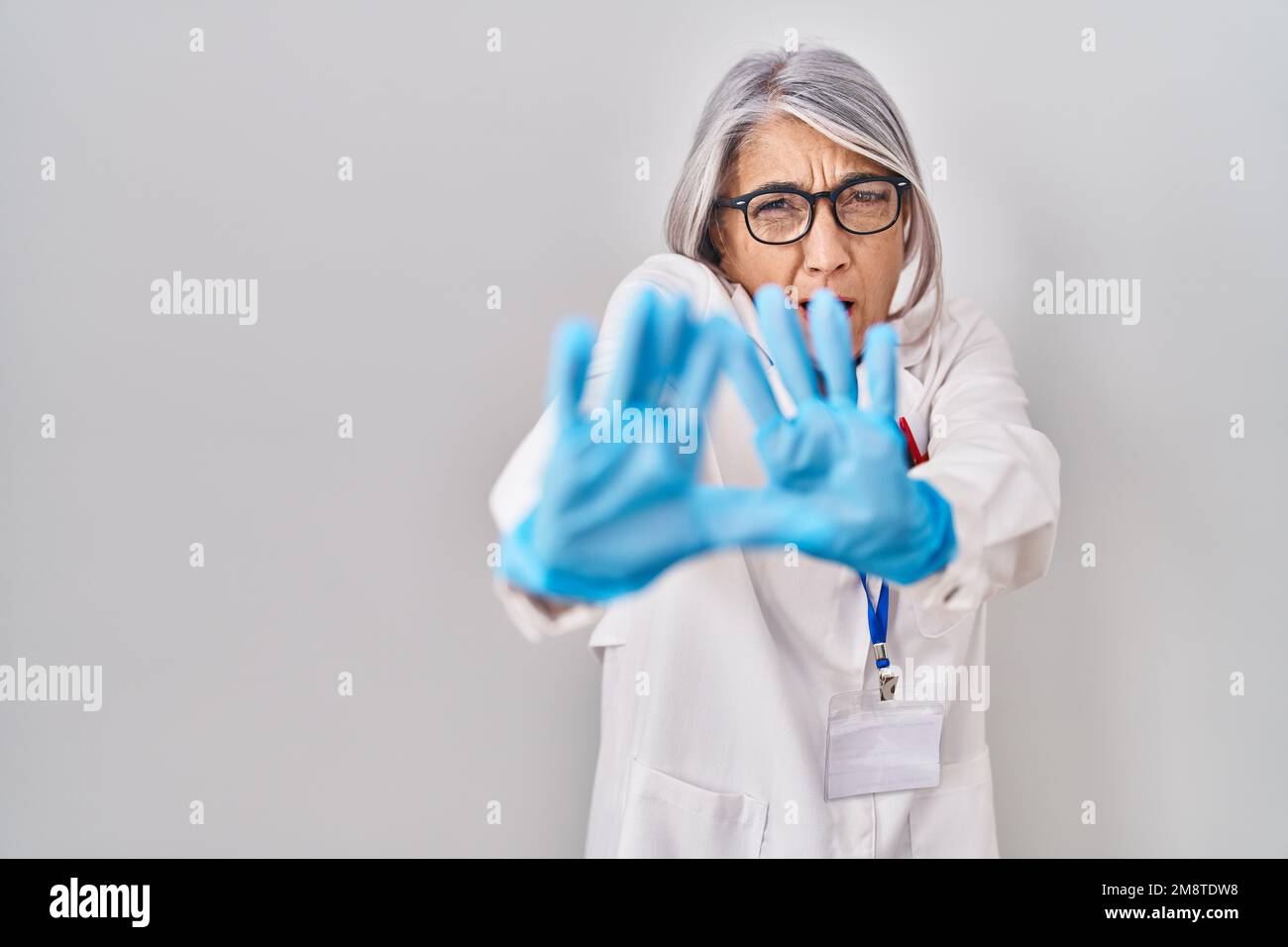 Middle age woman with grey hair wearing scientist robe afraid and ...
