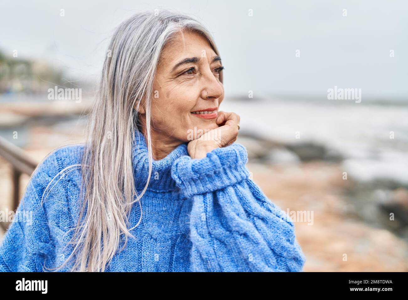 Middle age grey-haired woman smiling confident looking to the side at ...