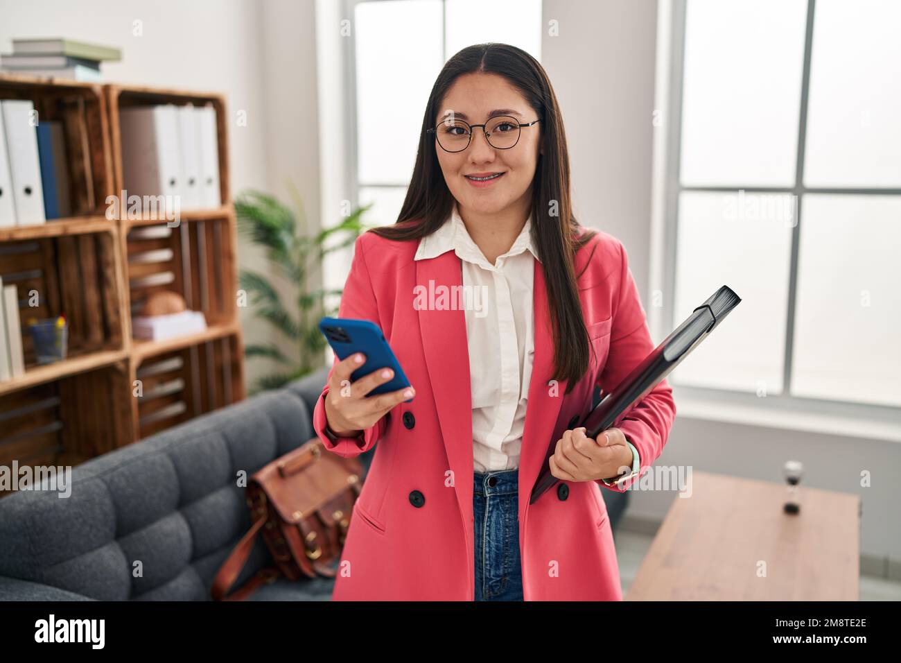 Young hispanic woman psychologist using smartphone at psychology center ...