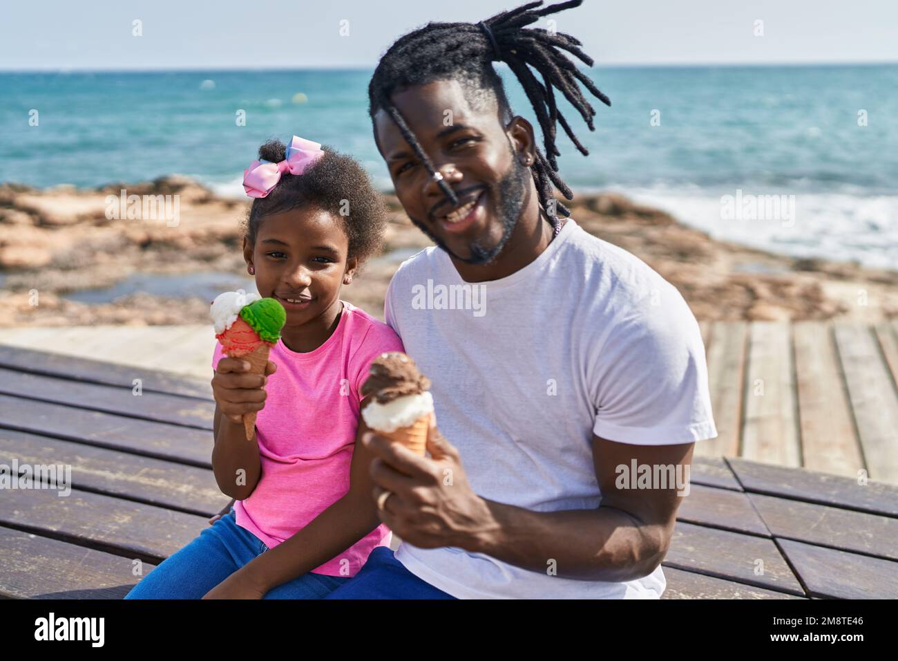 Father And Daughter Eating Ice Cream Sitting Together On Bench At