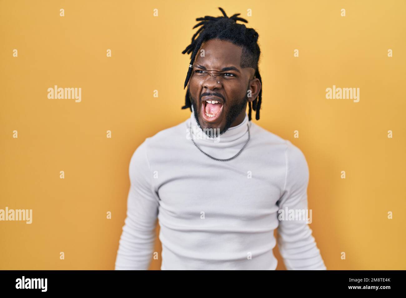 African man with dreadlocks wearing turtleneck sweater over yellow ...