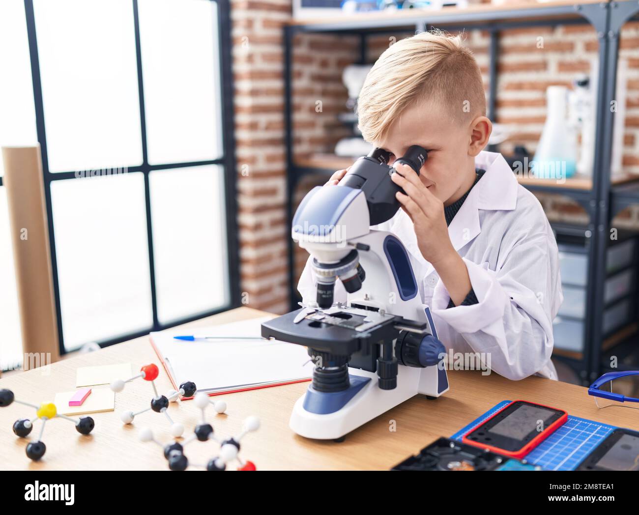 Adorable toddler student using microscope standing at classroom Stock ...