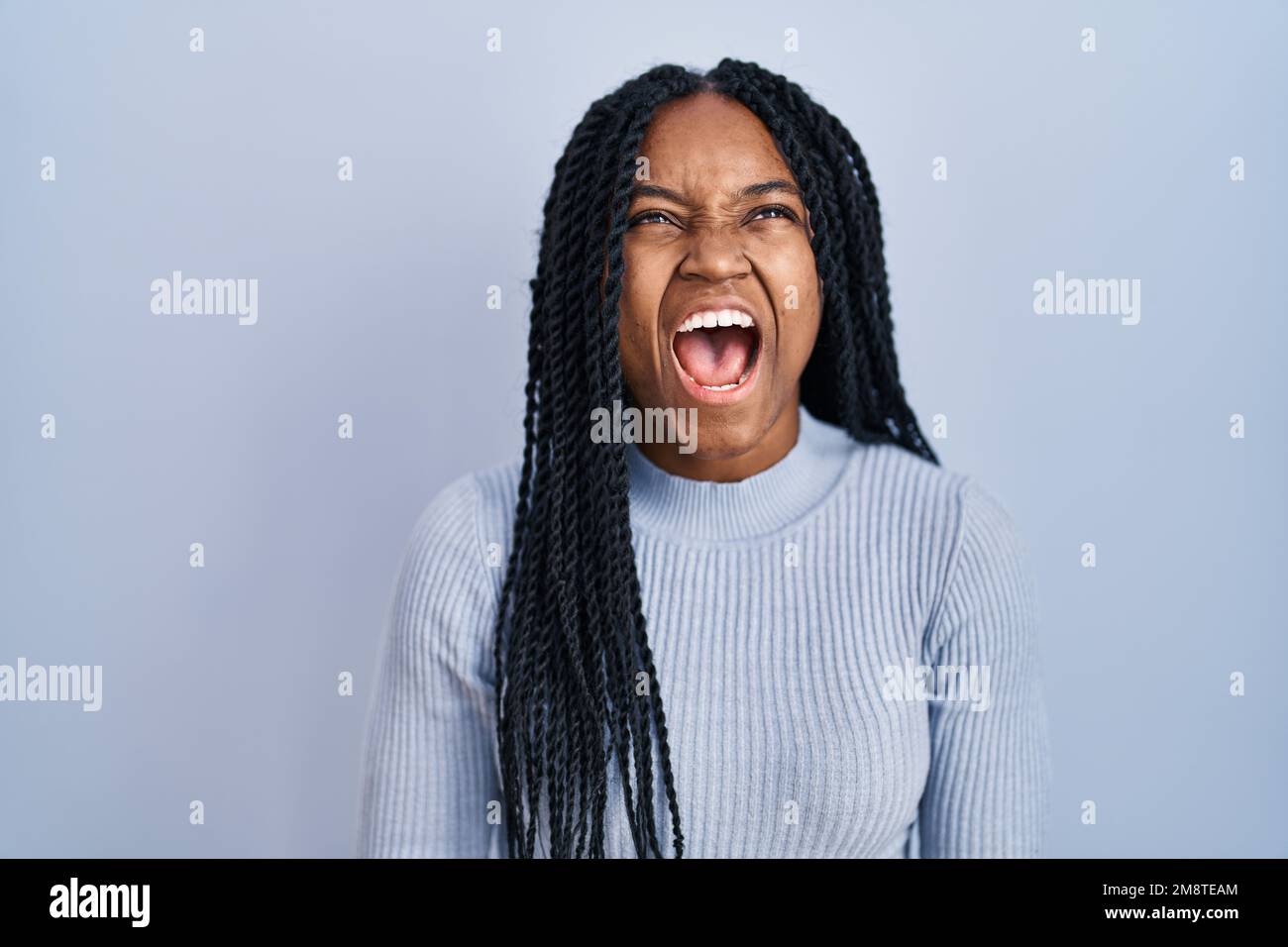 African american woman standing over blue background angry and mad ...
