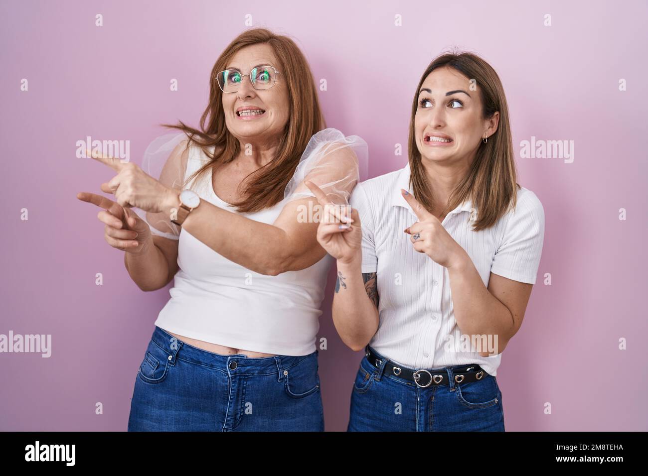 Hispanic mother and daughter wearing casual white t shirt over pink ...