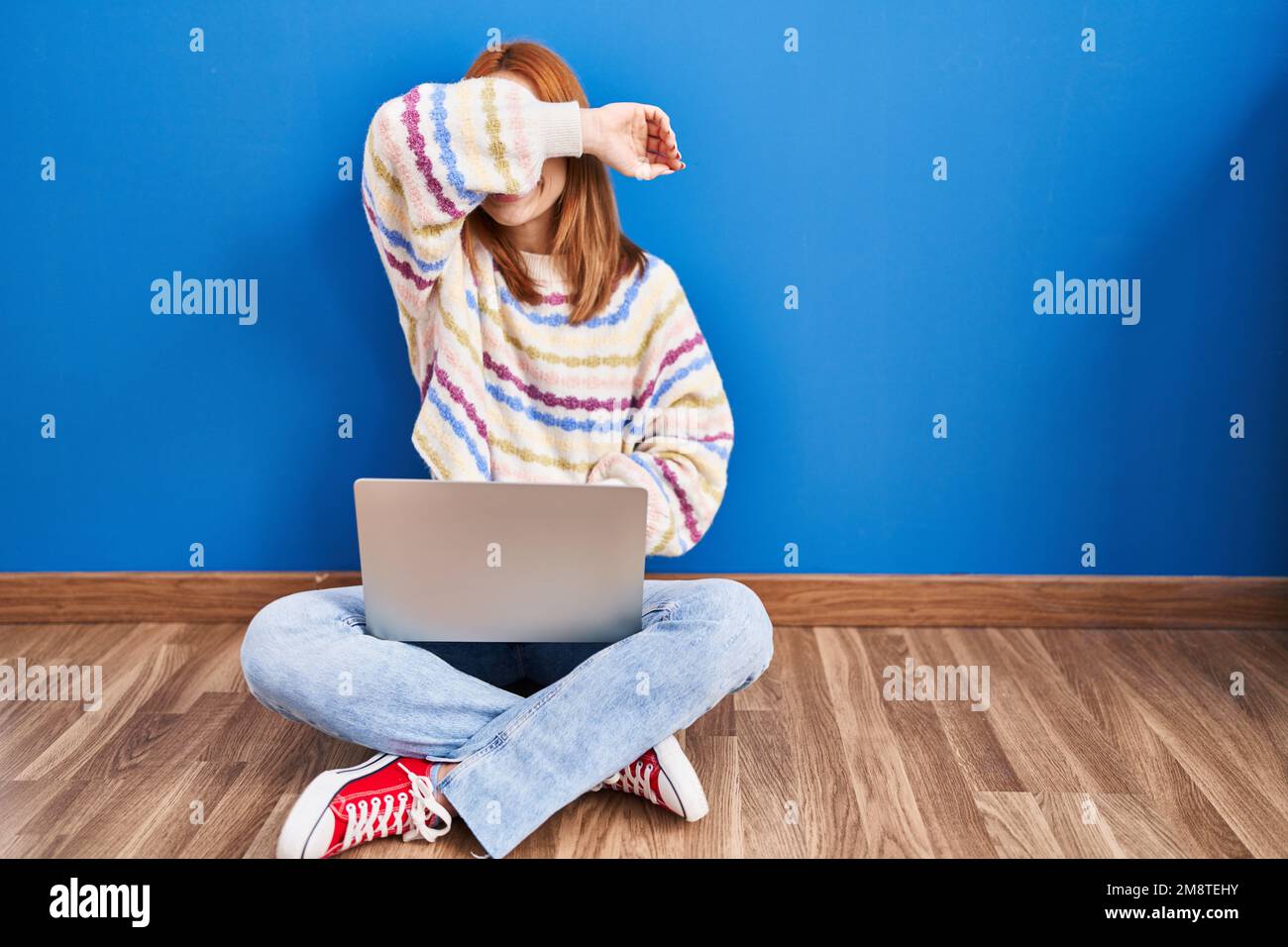Young woman using laptop at home sitting on the floor smiling cheerful ...
