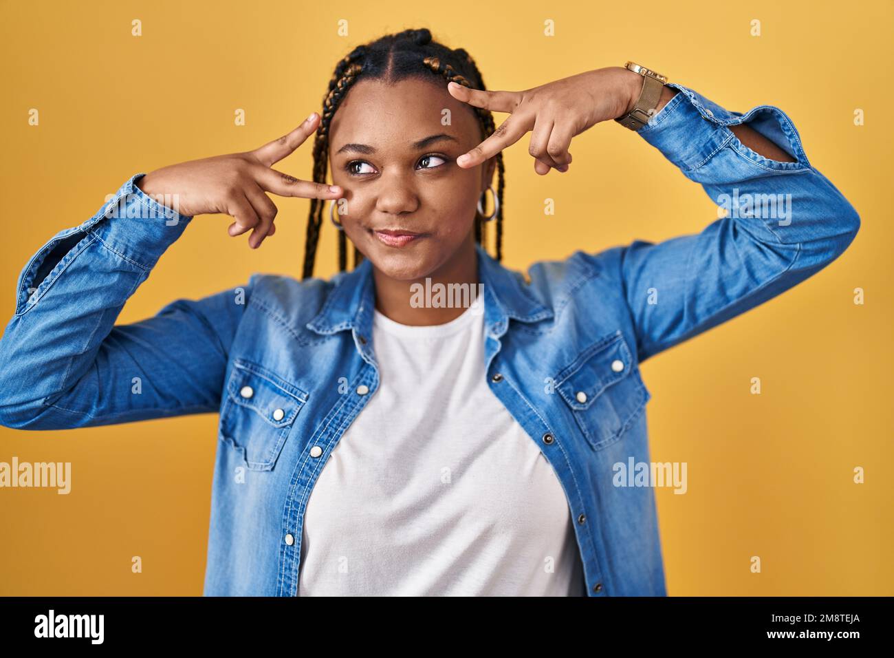 African american woman with braids standing over yellow background ...