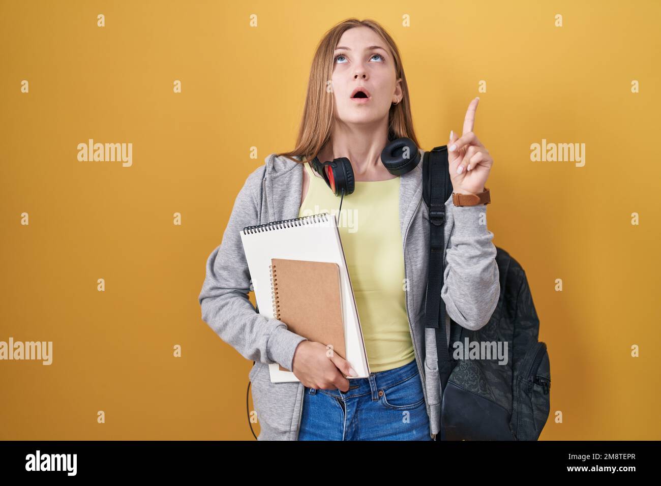 Young caucasian woman wearing student backpack and holding books amazed ...