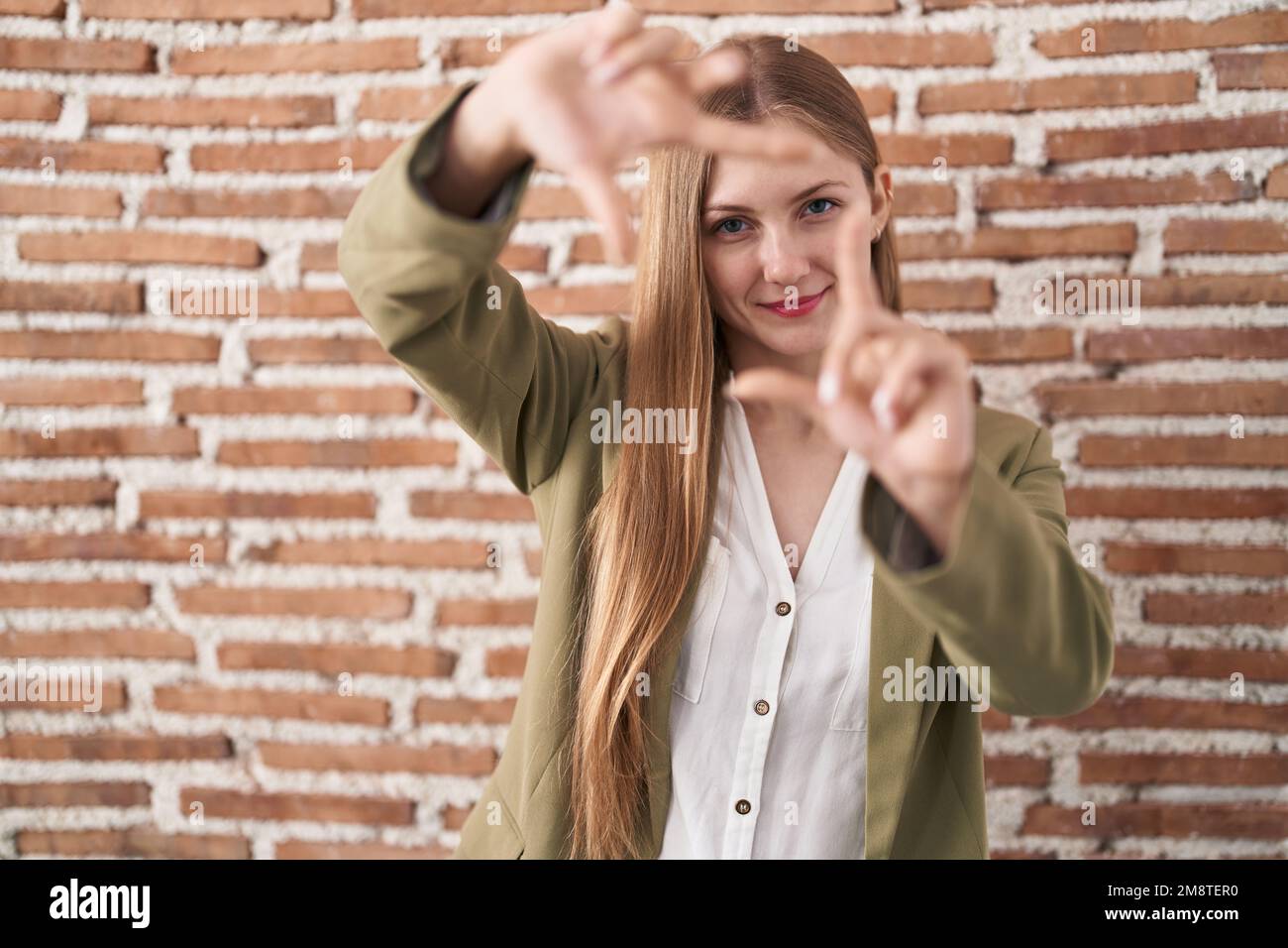 Young caucasian woman standing over bricks wall background smiling ...