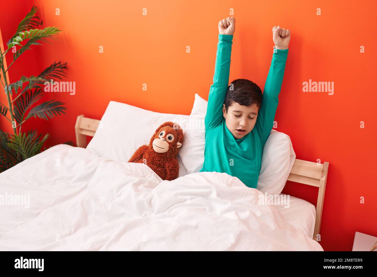Adorable hispanic boy waking up stretching arms at bedroom Stock Photo ...