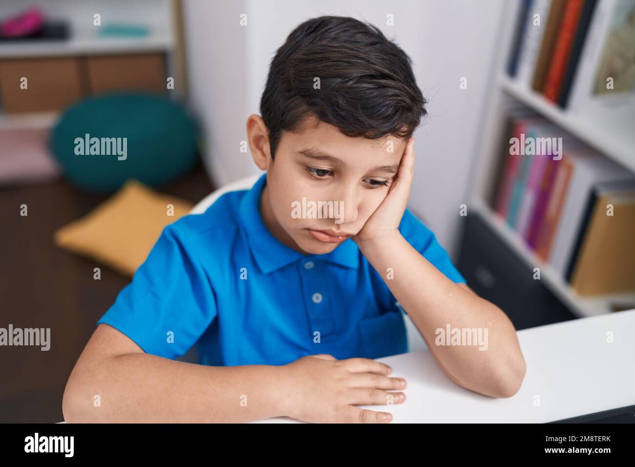Adorable hispanic boy student using computer with tired expression at ...