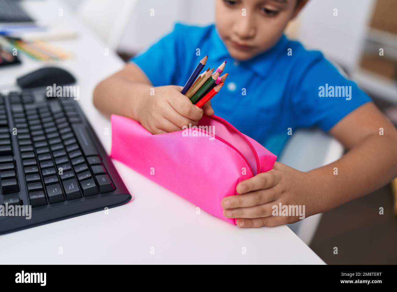 Adorable hispanic boy student holding pencil of case at classroom Stock ...