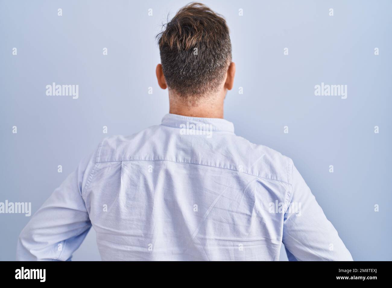 Middle age caucasian man standing over blue background standing ...