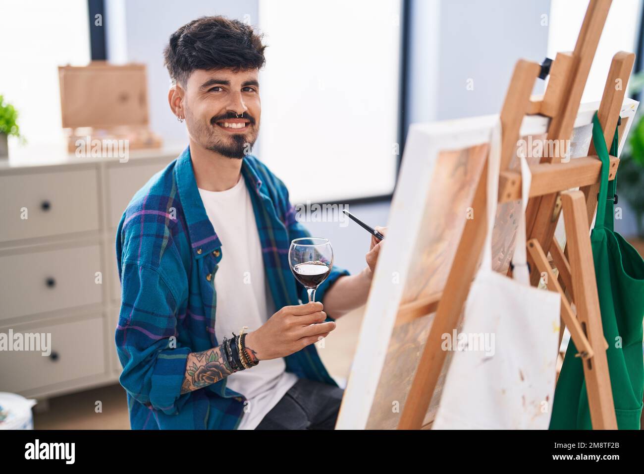 Young hispanic man artist drinking wine drawing at art studio Stock ...