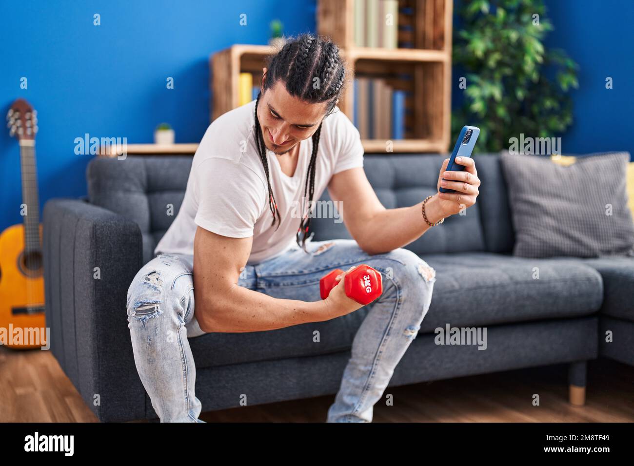 Young man training with dumbbell make selfie by smartphone at home ...