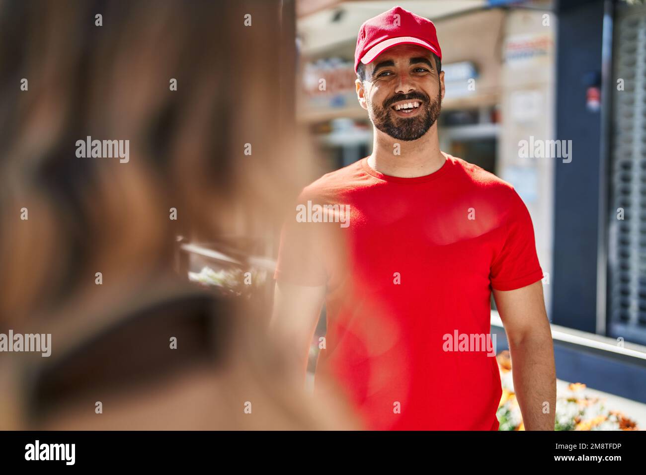 Young hispanic man courier smiling confident standing at street Stock ...