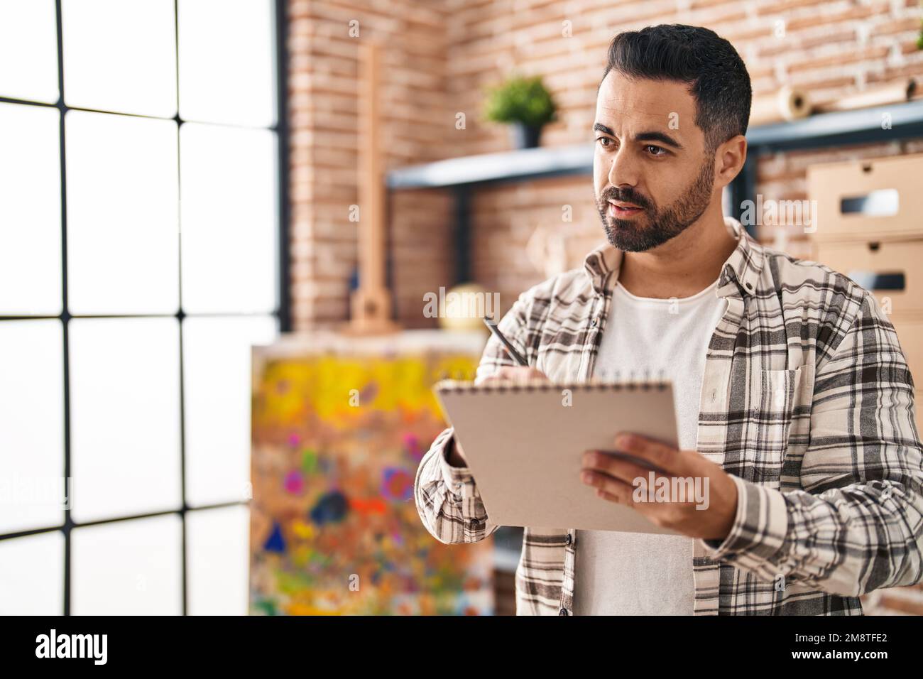 Young hispanic man drawing on notebook at art studio Stock Photo - Alamy