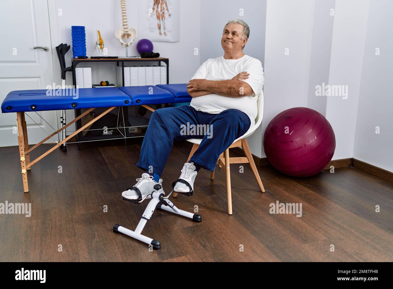 Senior caucasian man at physiotherapy clinic using pedal exerciser ...