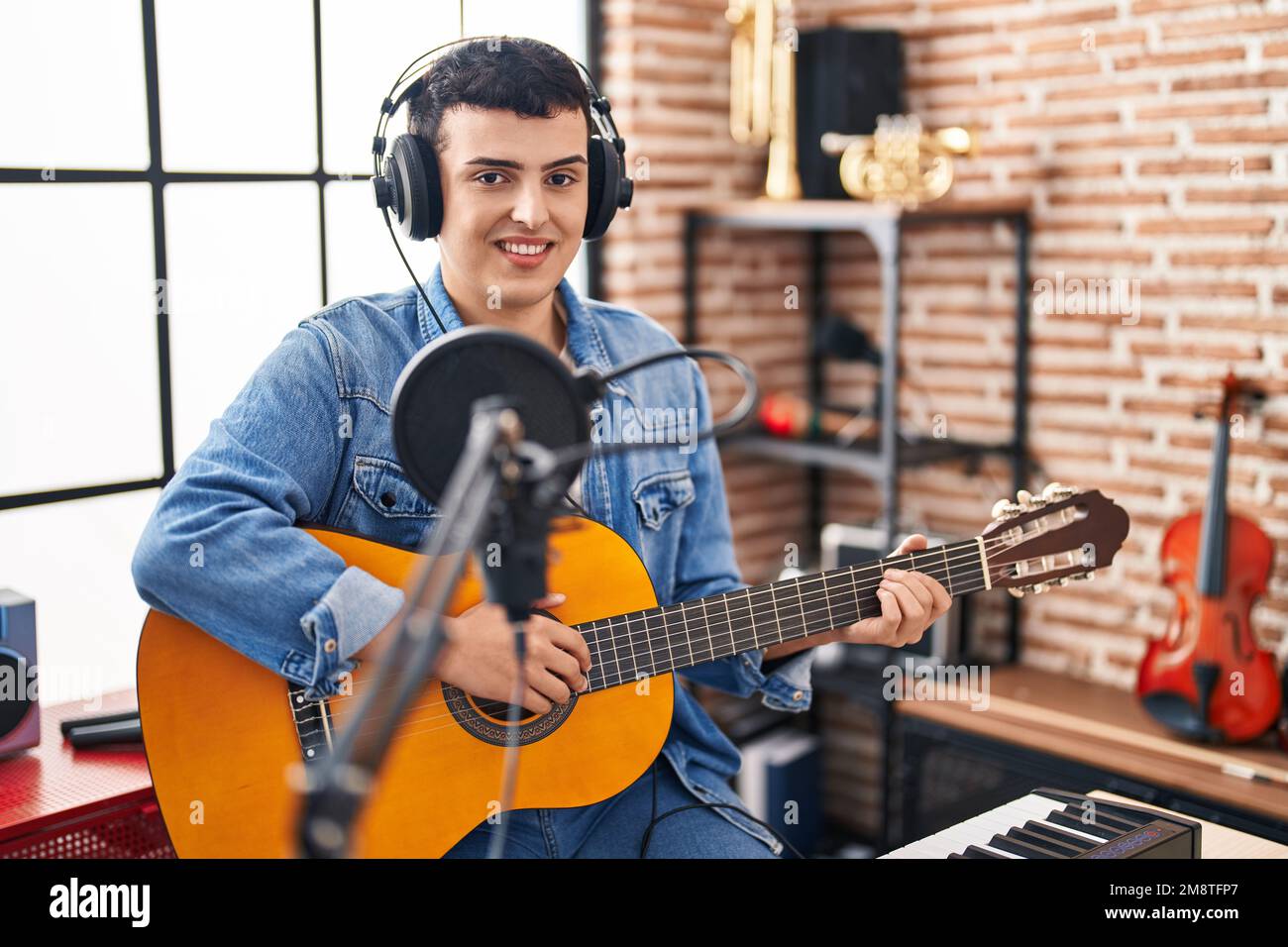 Young non binary man musician singing song playing classical guitar at ...