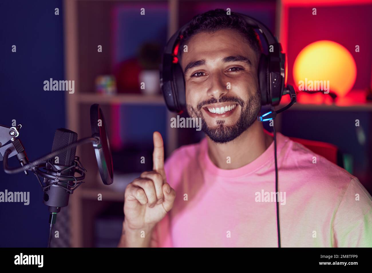 Hispanic young man playing video games wearing headphones smiling with ...
