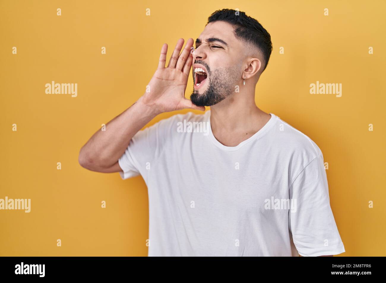 Young handsome man wearing casual t shirt over yellow background ...
