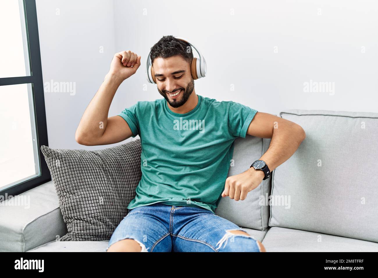Young arab man listening to music sitting on sofa at home Stock Photo ...