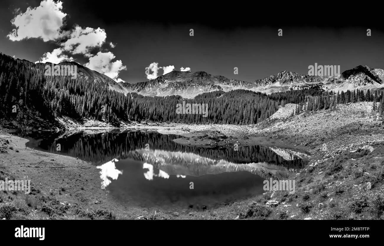 Grayscale shot of a lake, with reflections of its surrounding mountains ...