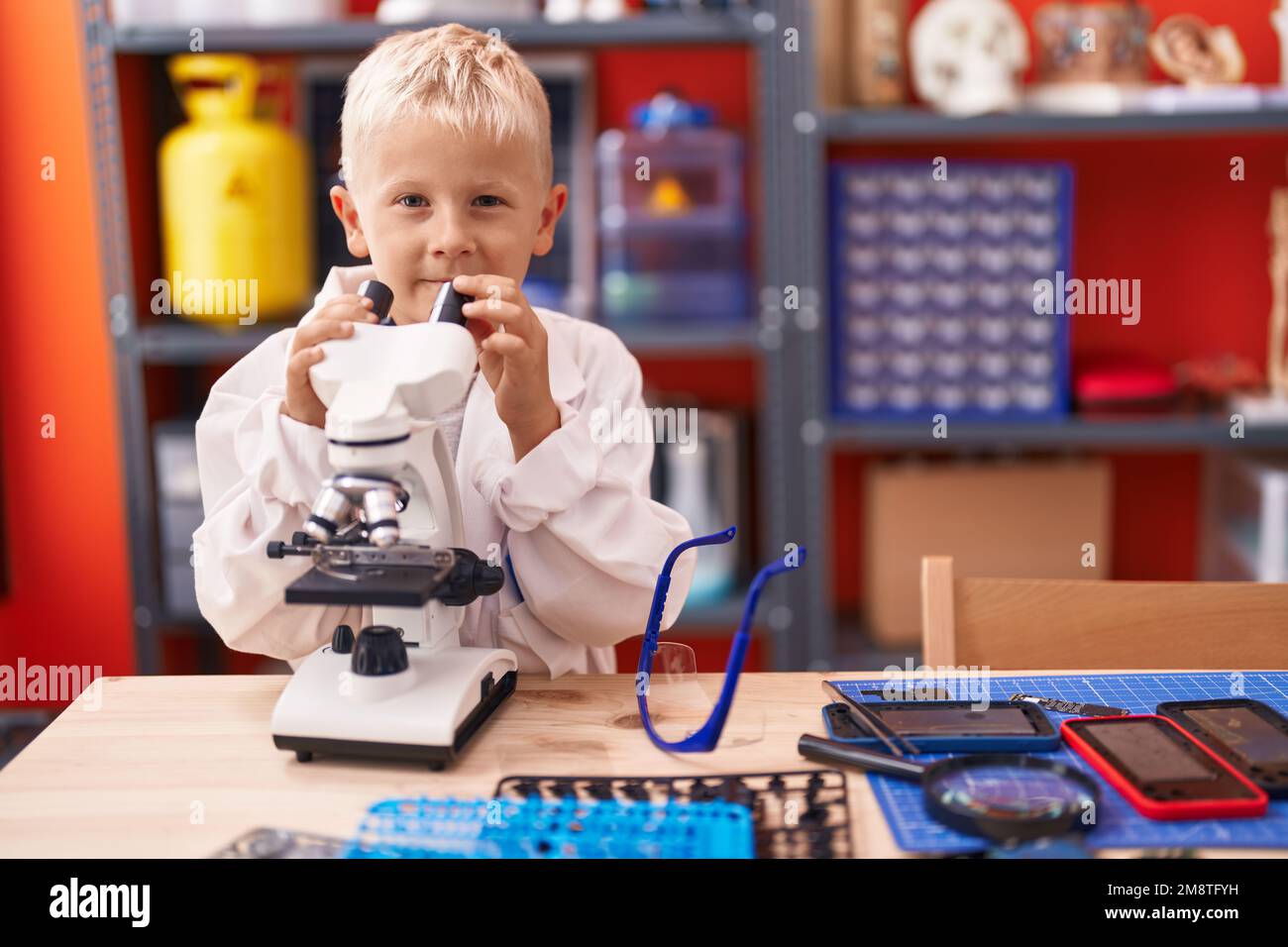 Adorable toddler student using microscope standing at classroom Stock ...