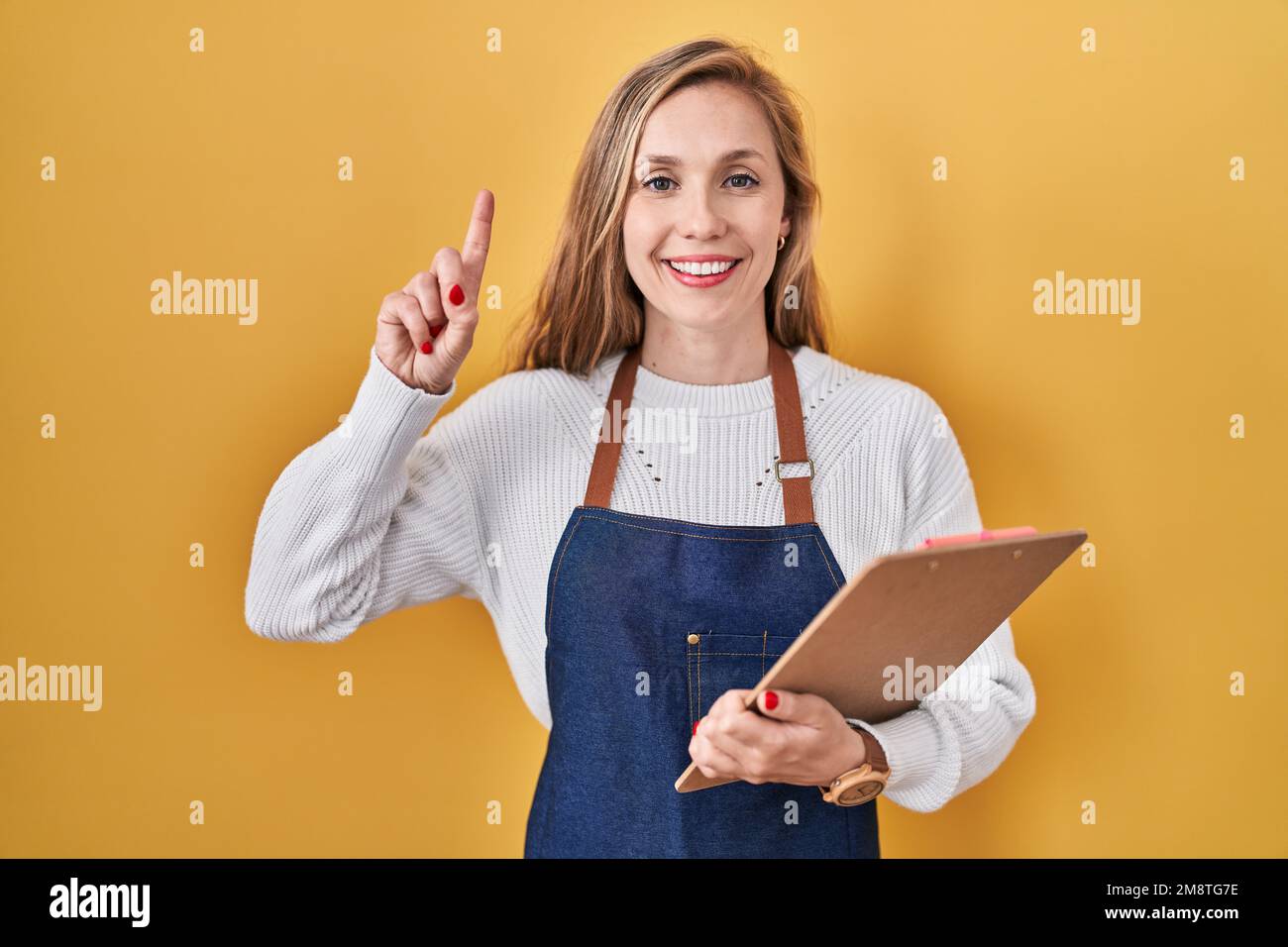 Young blonde woman wearing professional waitress apron holding ...