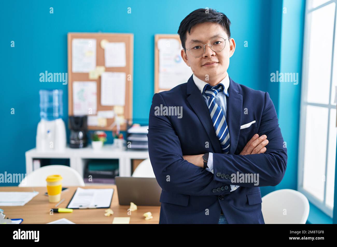 Young chinese man business worker standing with relaxed expression and ...