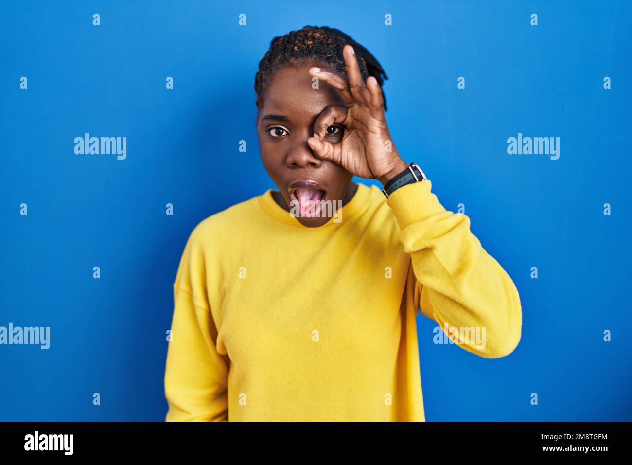 Beautiful black woman standing over blue background doing ok gesture ...