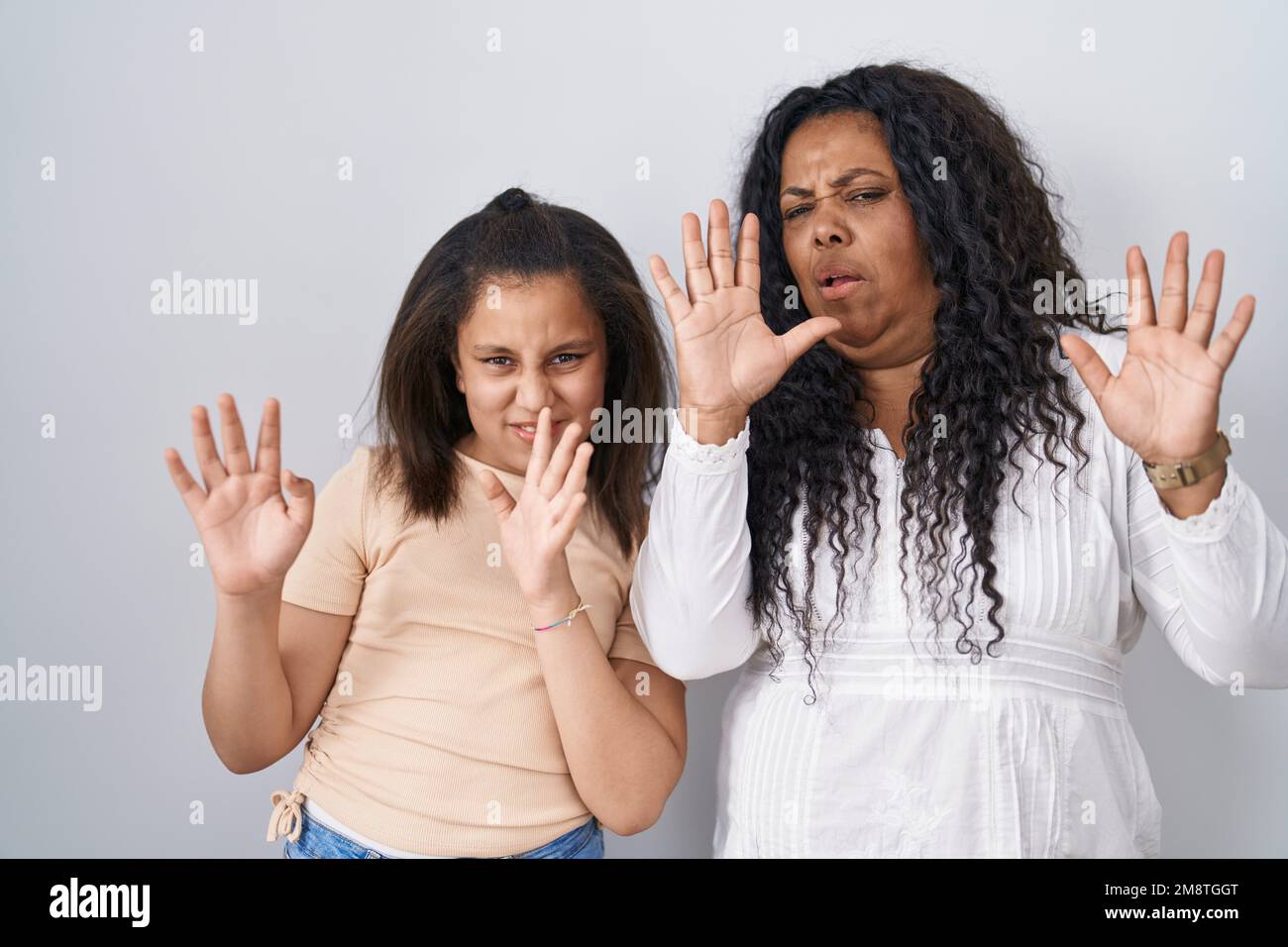 Mother and young daughter standing over white background moving away ...